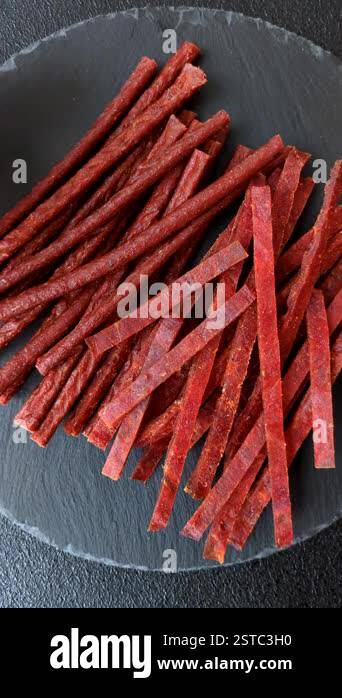 Jerky dried fish sticks with salt and spices on a dark concrete ...
