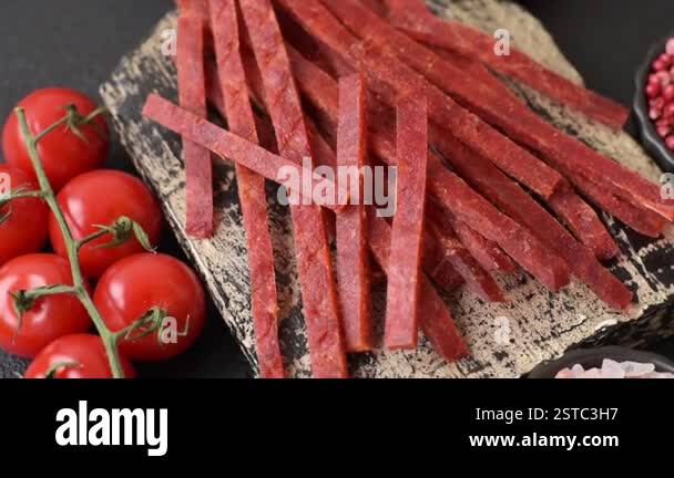Jerky dried fish sticks with salt and spices on a dark concrete ...