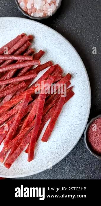 Jerky dried fish sticks with salt and spices on a dark concrete ...