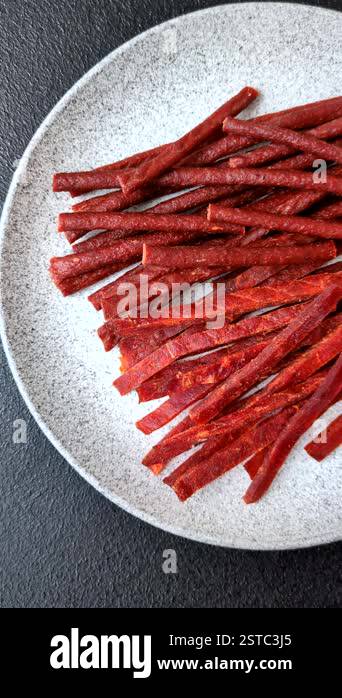 Jerky dried fish sticks with salt and spices on a dark concrete ...