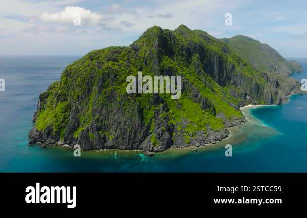 Tapiutan Island with green hills surrounded by blue sea. El Nido ...