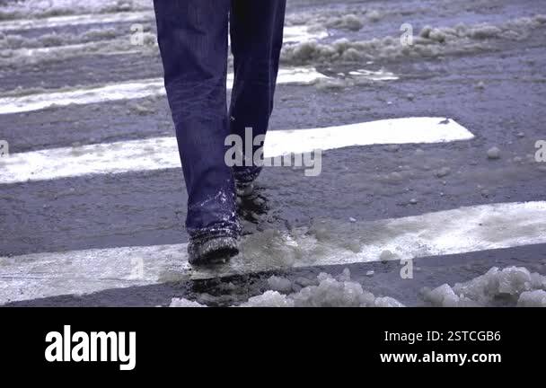 Pedestrian walk away from camera in slow motion on over snow and ice ...