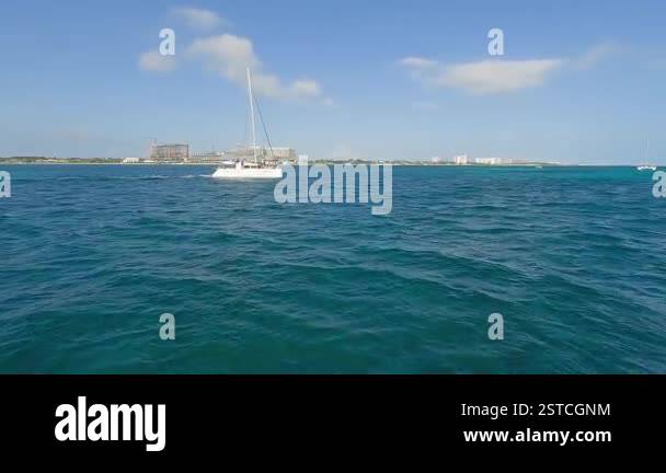 A serene scene unfolds as a sailboat glides over shimmering water ...