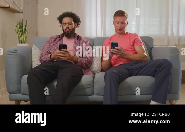 Two friends from different backgrounds are comfortably seated side by ...