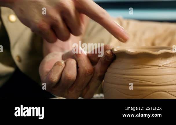 Close up hand man finger craftsman master shaping modeling clay potter ...
