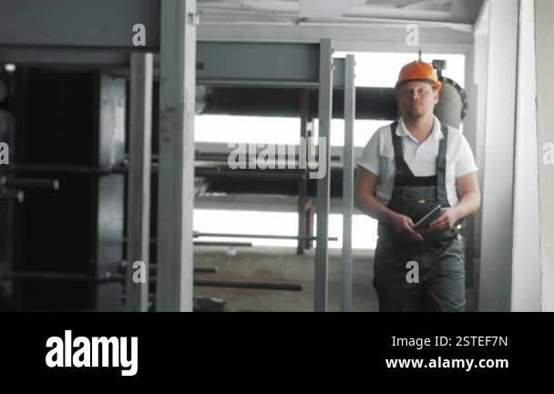 An engineer or worker at a gas station in a work uniform uses a digital ...