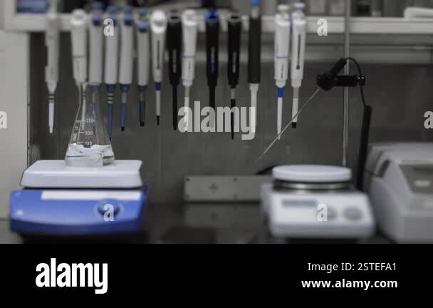 A laboratory magnetic mixer mixes reagents in a glass flask in a ...