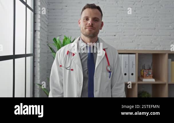 A confident hispanic male doctor in a clinic office gives the ok sign ...