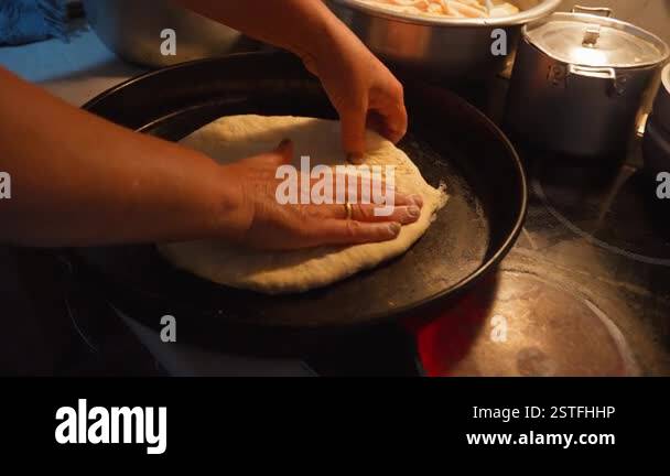 Skilled hands work with dough in hot pan, carefully shaping and ...