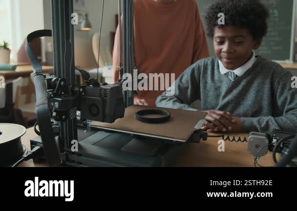 Two classmates feeling excited, using 3D printer for first time during ...