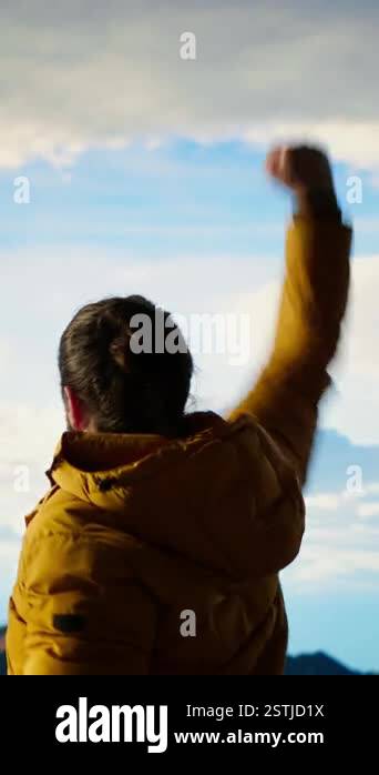 Vertical Video Hiker dressed in warm outdoor gear celebrates reaching ...