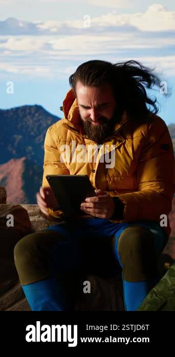 Vertical Video Male hiker struggles to work online in windy conditions ...
