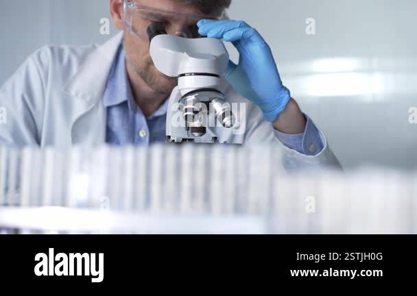 Male scientist researcher wearing blue gloves, protective glasses is ...