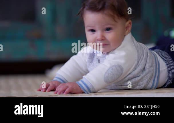 Baby lying on stomach, looking up and smiling, playful and engaged in ...