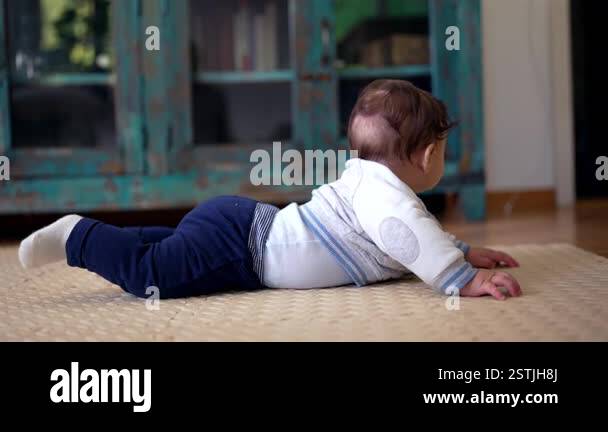 Baby on tummy lifting head, focused expression, exploring living room ...