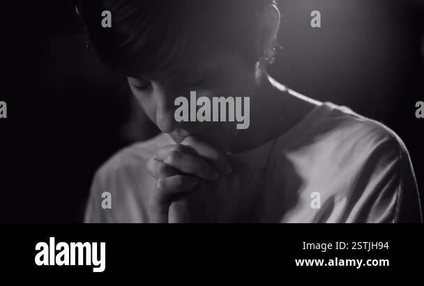Woman in deep prayer, head bowed and hands clasped, peaceful spiritual ...
