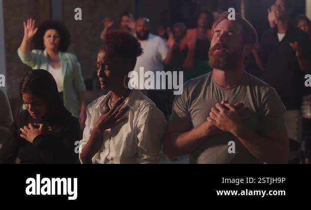 Congregation in prayer, diverse group standing with hands on hearts and ...
