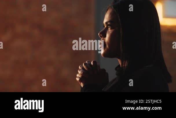 Side profile of a young woman praying with hands clasped, serene ...