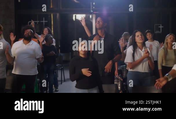 Group worship in a church setting, people standing in prayer, hands ...