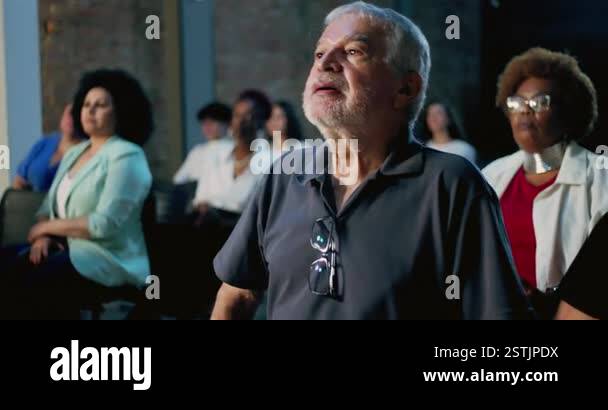 Man in church with illuminated cross in background, praying with raised ...
