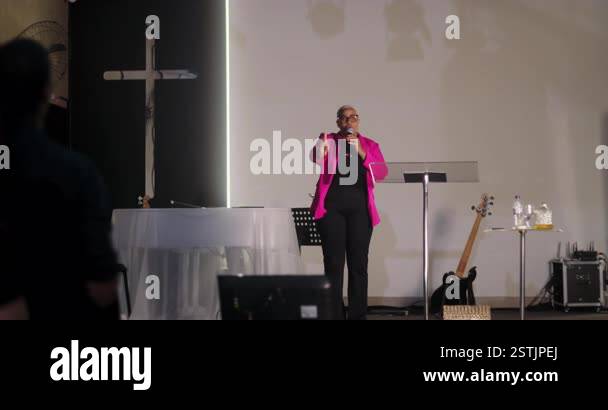 Speaker delivering sermon, holding microphone, addressing congregation ...