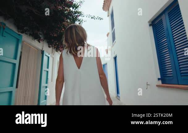 Cinematic following shot of young woman explore small quaint town on ...