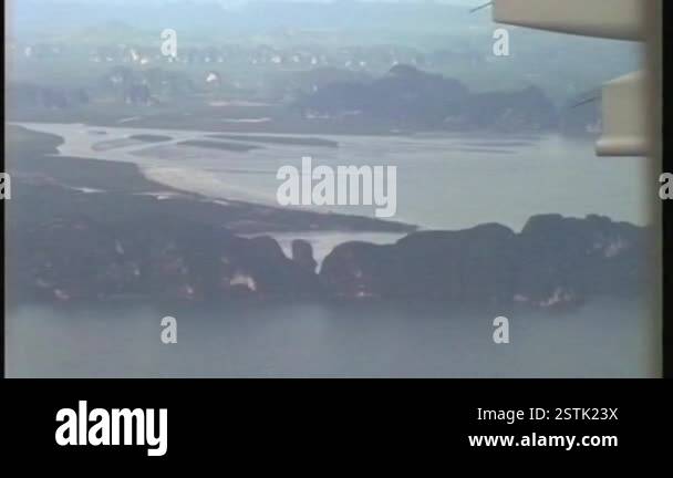 An aerial view from a plane window reveals a mountainous region with a ...