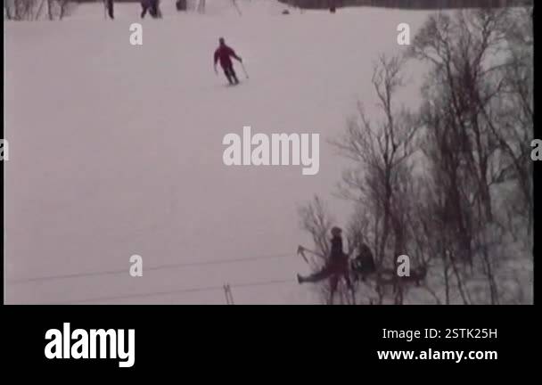 A VHS home video captures a skier slowly gliding down a snow-covered slope toward the camera ...