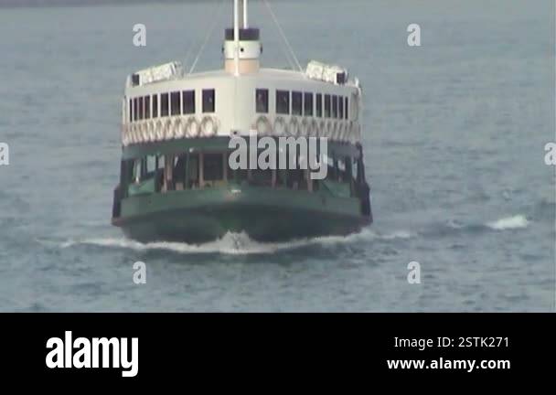 A close-up shot shows a ferry boat crossing calm, clear water, creating ...
