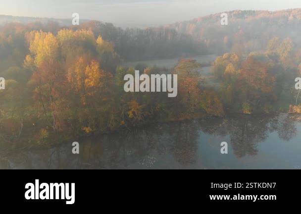 Aerial scene of beautiful foggy lake in autumn with yellow and orange ...