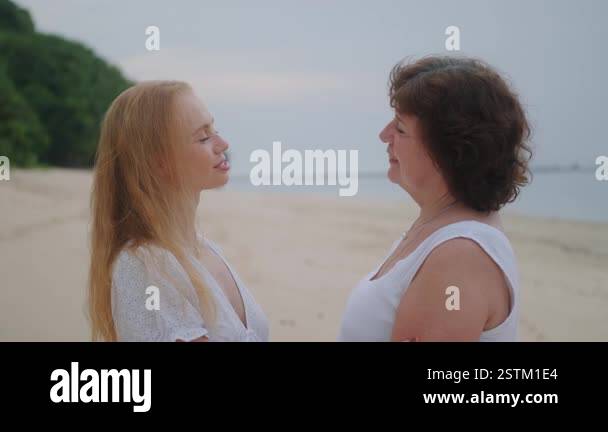 Side view of a senior woman smiling and tenderly kissing her adult ...