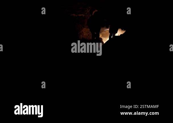 Dark cave illuminates bold explorer silhouettes. Journey into a realm ...