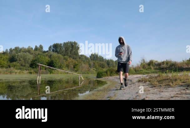 Caucasian Man Walks With Smartphone Near River. Hiking on Nature. Slow ...