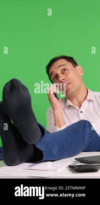 Lazy employee is talking on the phone with his feet up on the table ...