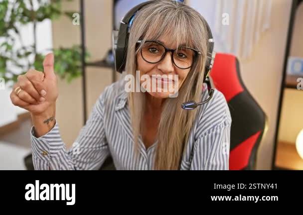 Joyful middle age female gamer, rocking grey hair and cool headphones ...