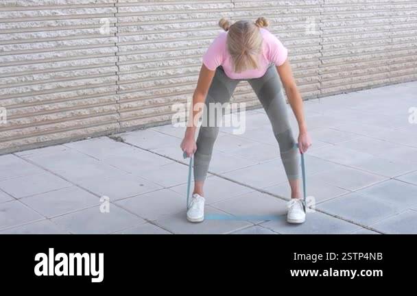 In an outdoor environment, a woman dressed in activewear performs a ...