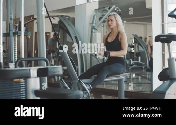 Strong woman demonstrates slow motion rowing exercise in gym setting ...