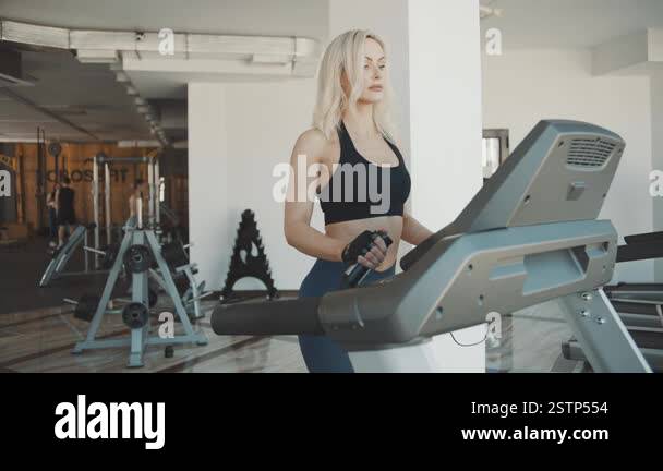 Girl working out on treadmill in gym with modern equipment and smooth ...