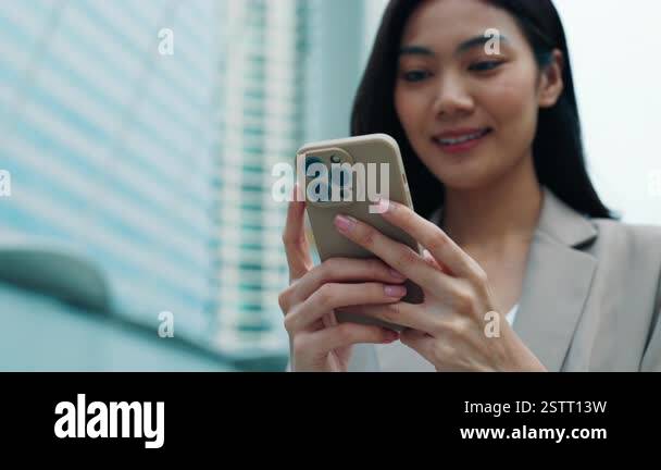 Confident young businesswoman in a beige blazer using her smartphone ...