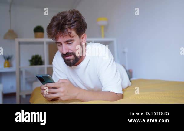 Relaxed young caucasian man resting comfortably on bed, casually ...