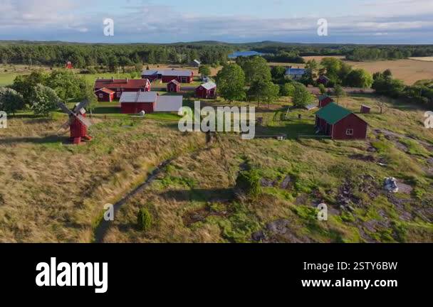 Red windmill perched on a hill overlooks traditional red farm buildings ...