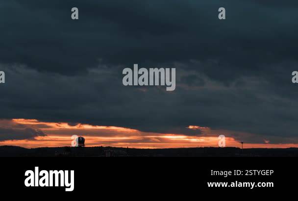 Timelapse of the mostly overcast sunset sky with brightly orange glow ...
