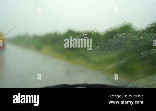 Rain drops on windshield and car wipers are removing water. Driving in ...