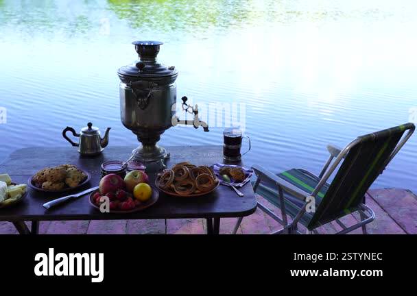 Vintage metal tea samovar with white smoke and food on the table near ...