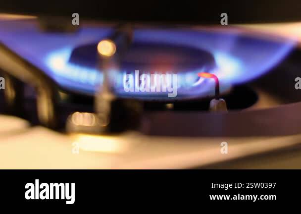 Gas stove flame. Close up of a gas stove burner igniting with a blue ...