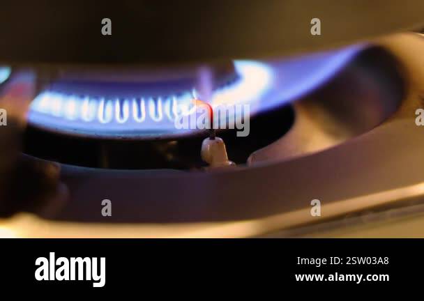 Gas stove flame. Close up of a gas stove burner igniting with a blue ...