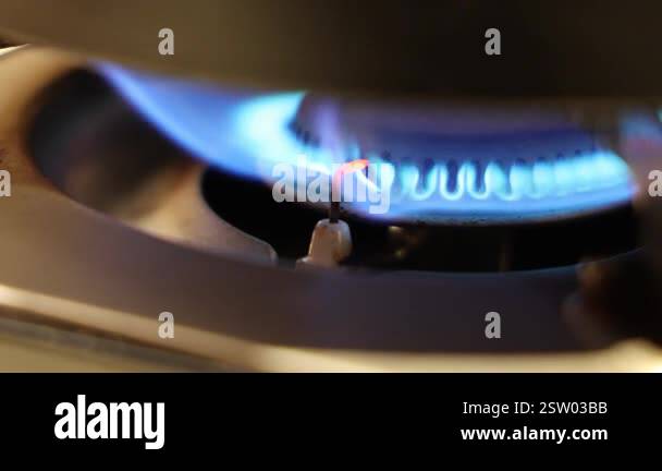 Gas stove flame. Close up of a gas stove burner igniting with a blue ...