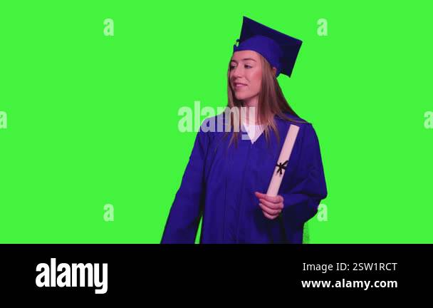 Female graduate wearing academic gown and holding diploma, pointing ...