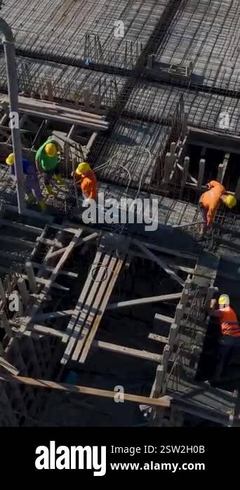 Engineers reviewing plans and workers building. Aerial footage of a ...
