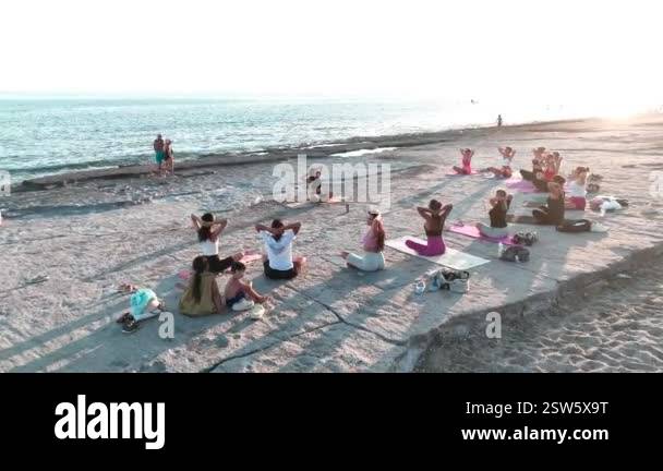 Girls practice yoga and meditation on a rocky beach, surrounded by the ...